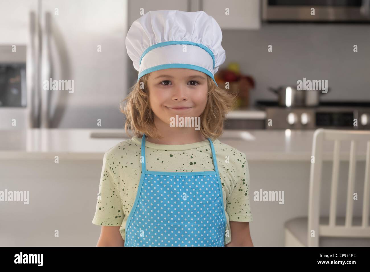 Portrait of funny child chef in kitchen. Kid chef cook wearing cooker ...