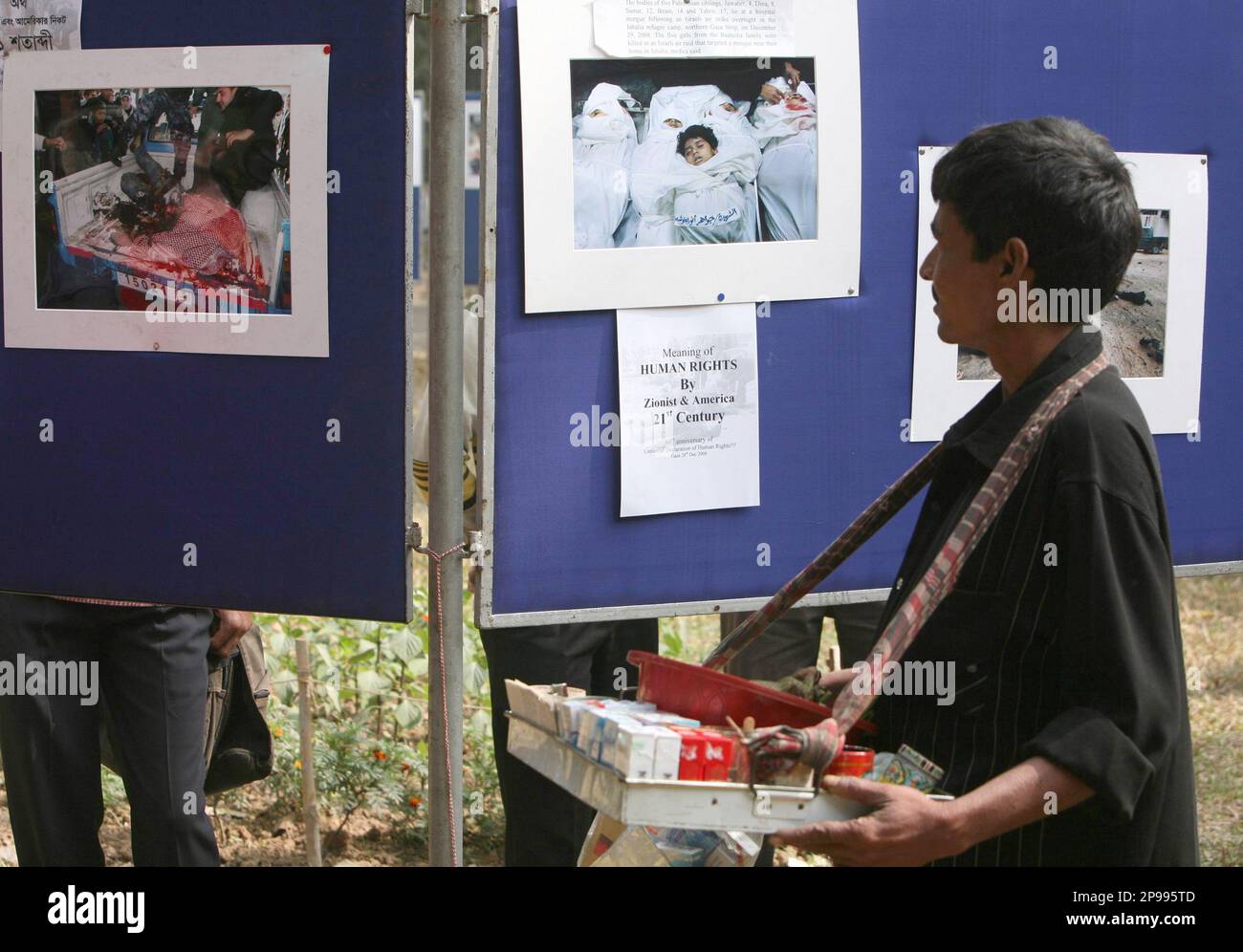 A Bangladeshi hawker looks at photos displaying alleged atrocities in ...