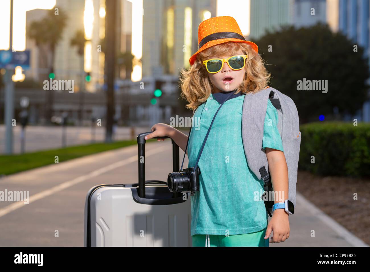 Child traveler standing and holding suitcase outdoor. Tourist kid boy ...