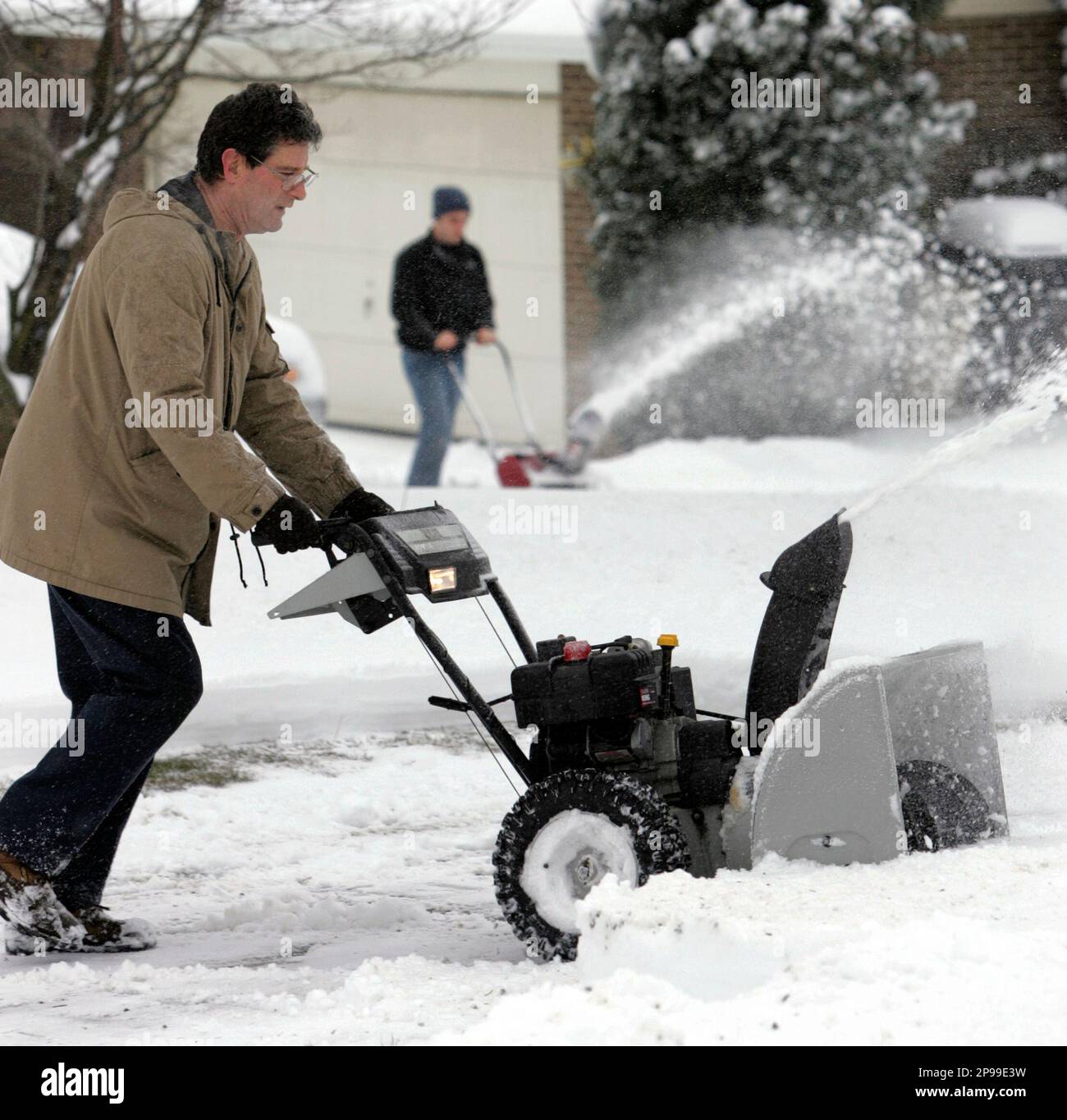 Neighbors Phil Samotus, left, and Nate Boros use their snowblowers to ...