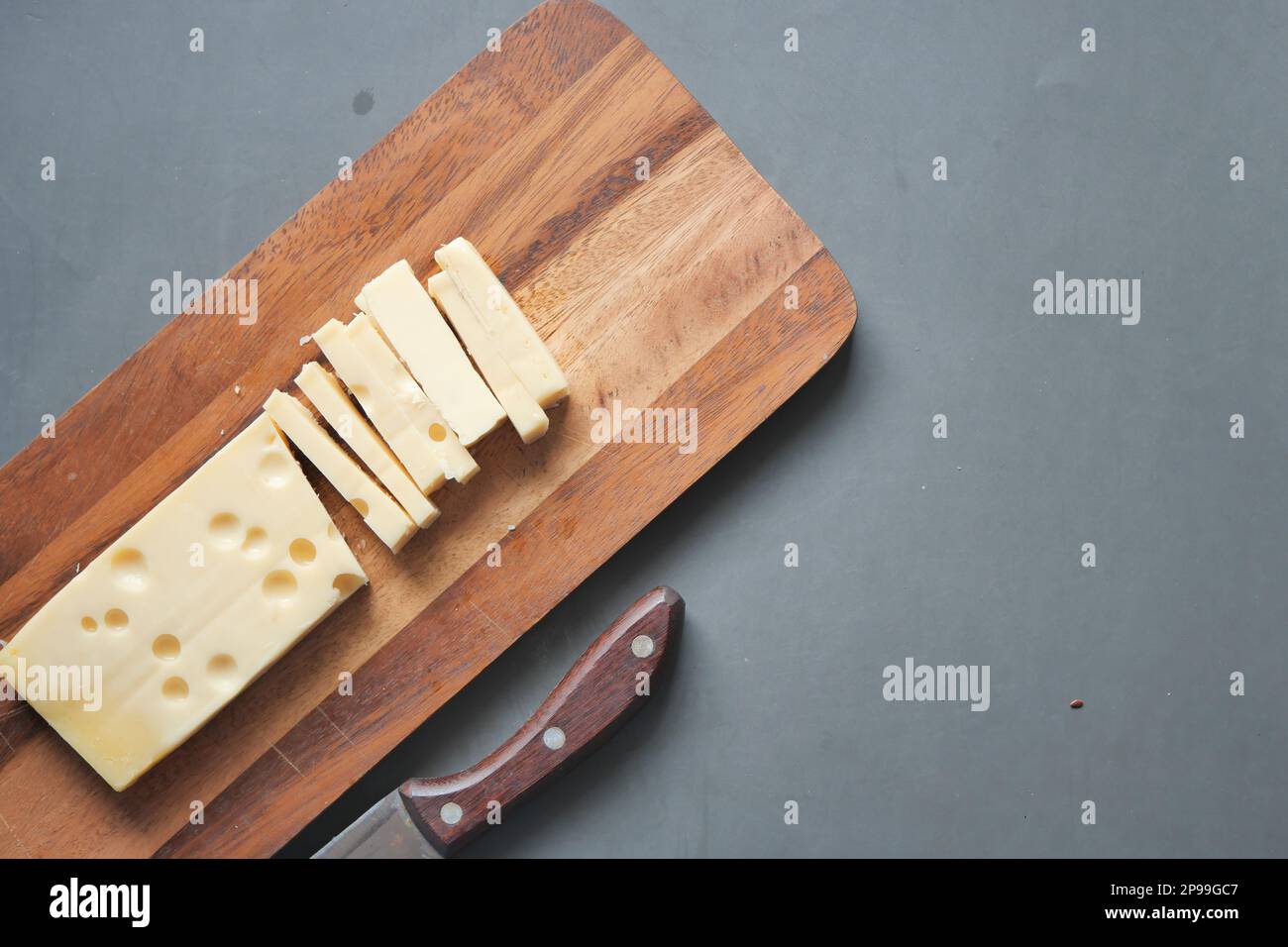 sliced cheese with holes on a chopping board on table Stock Photo - Alamy