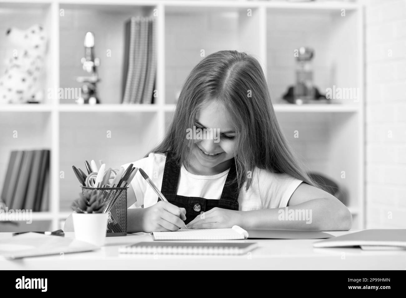happy child writing in copybook at school lesson in classroom wear ...