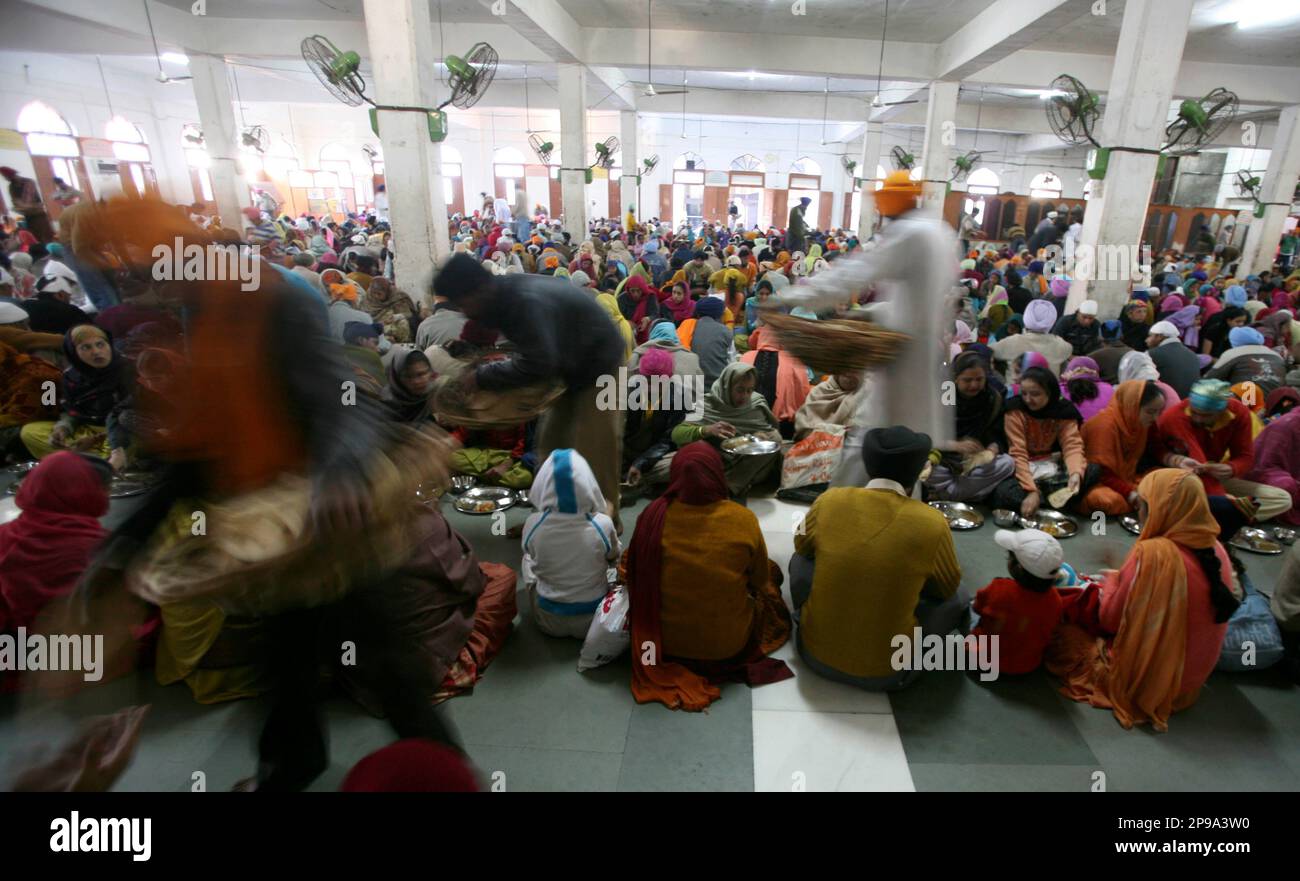 Sikh devotees eat inside a community kitchen at the Golden Temple ...