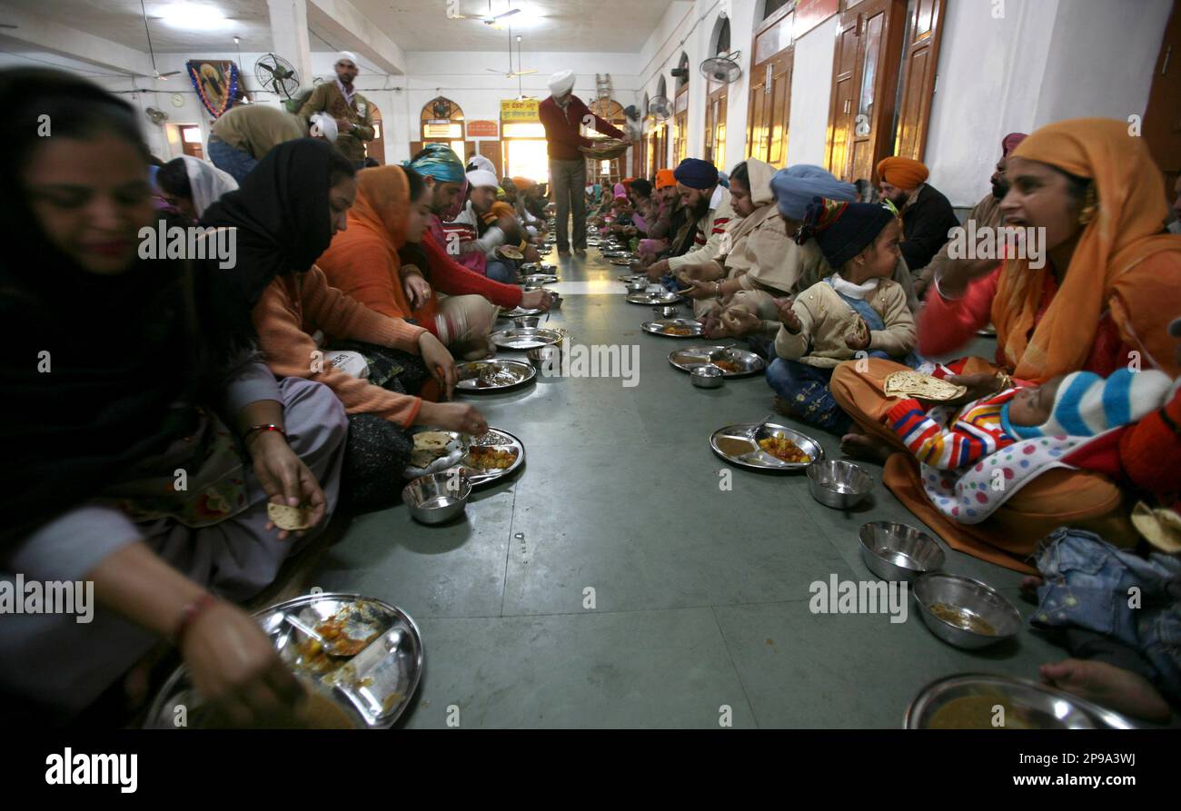 Sikh devotees eat inside a community kitchen at the Golden Temple ...