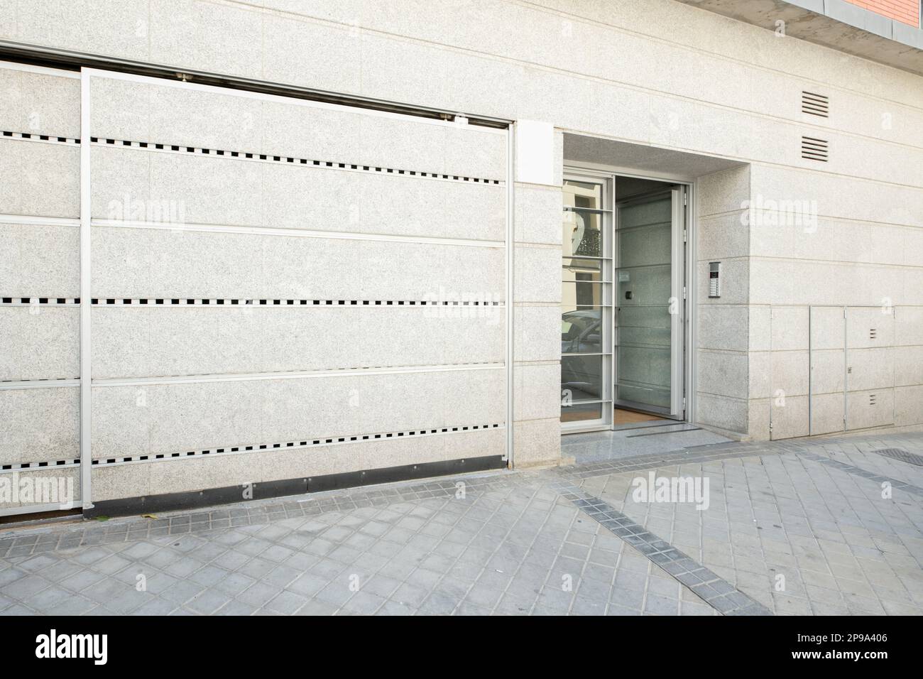 Facade of a building with an access portal and a folding garage door ...