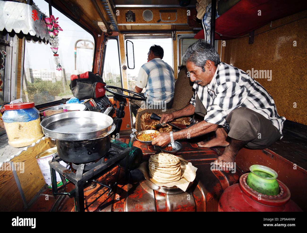 A truck driver cooks inside his truck in Hyderabad, India, Monday, Jan ...