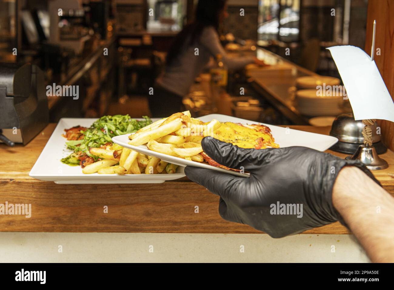 A cook passing the finished order through the serving hatch in the ...