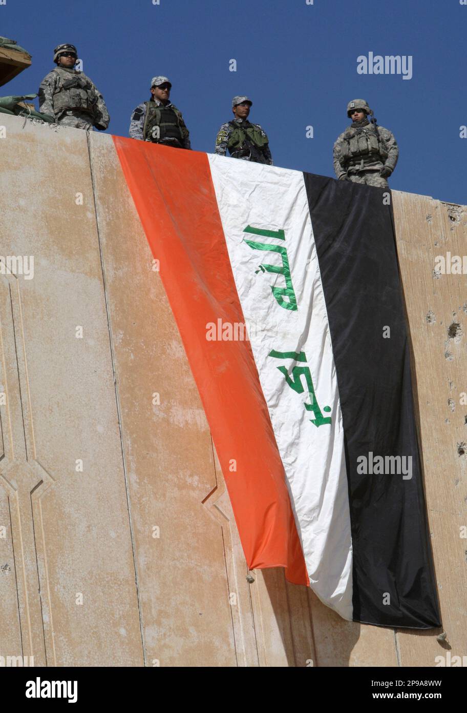 U.S. and Iraqi soldiers stand on top of a shopping center which housed ...