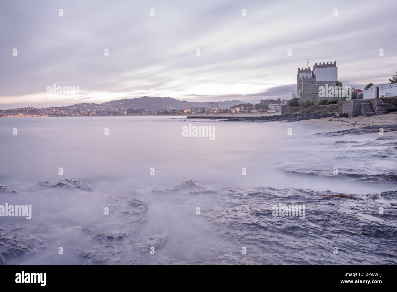 Long exposure image of rocks between sand and mist during high tide on ...