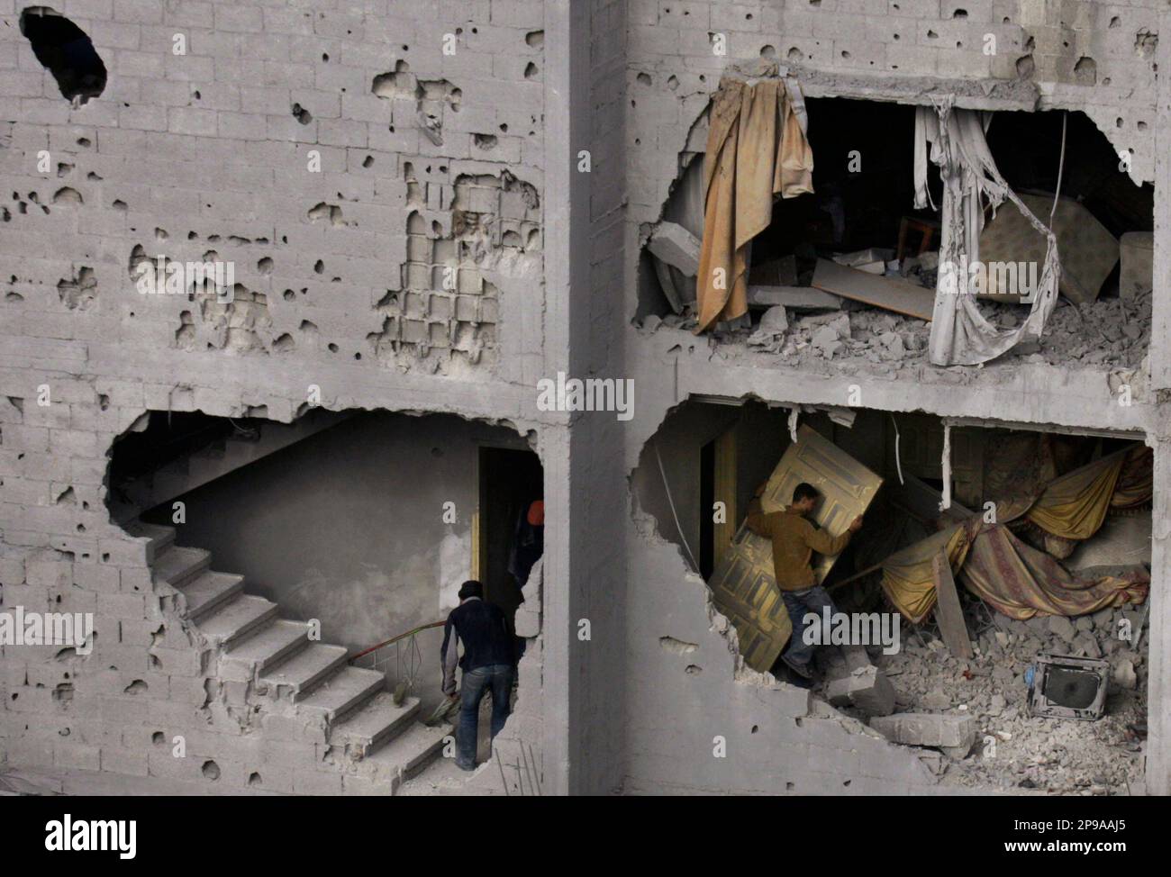 Palestinians collect belongings from the destroyed home of Hamas ...