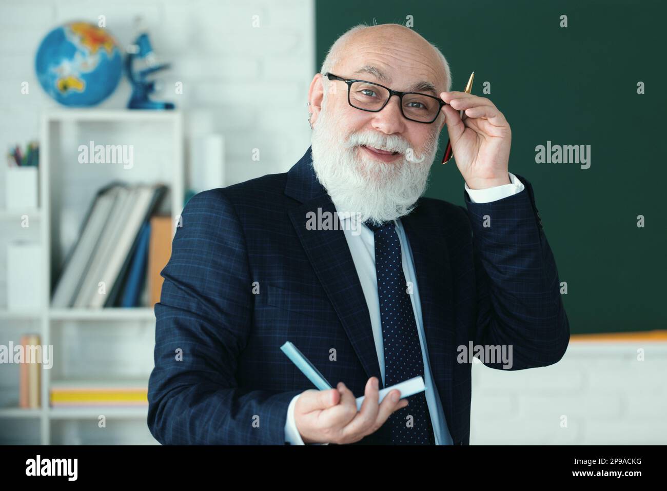 Elderly man teacher on a blank chalkboard during lesson, teaching class ...