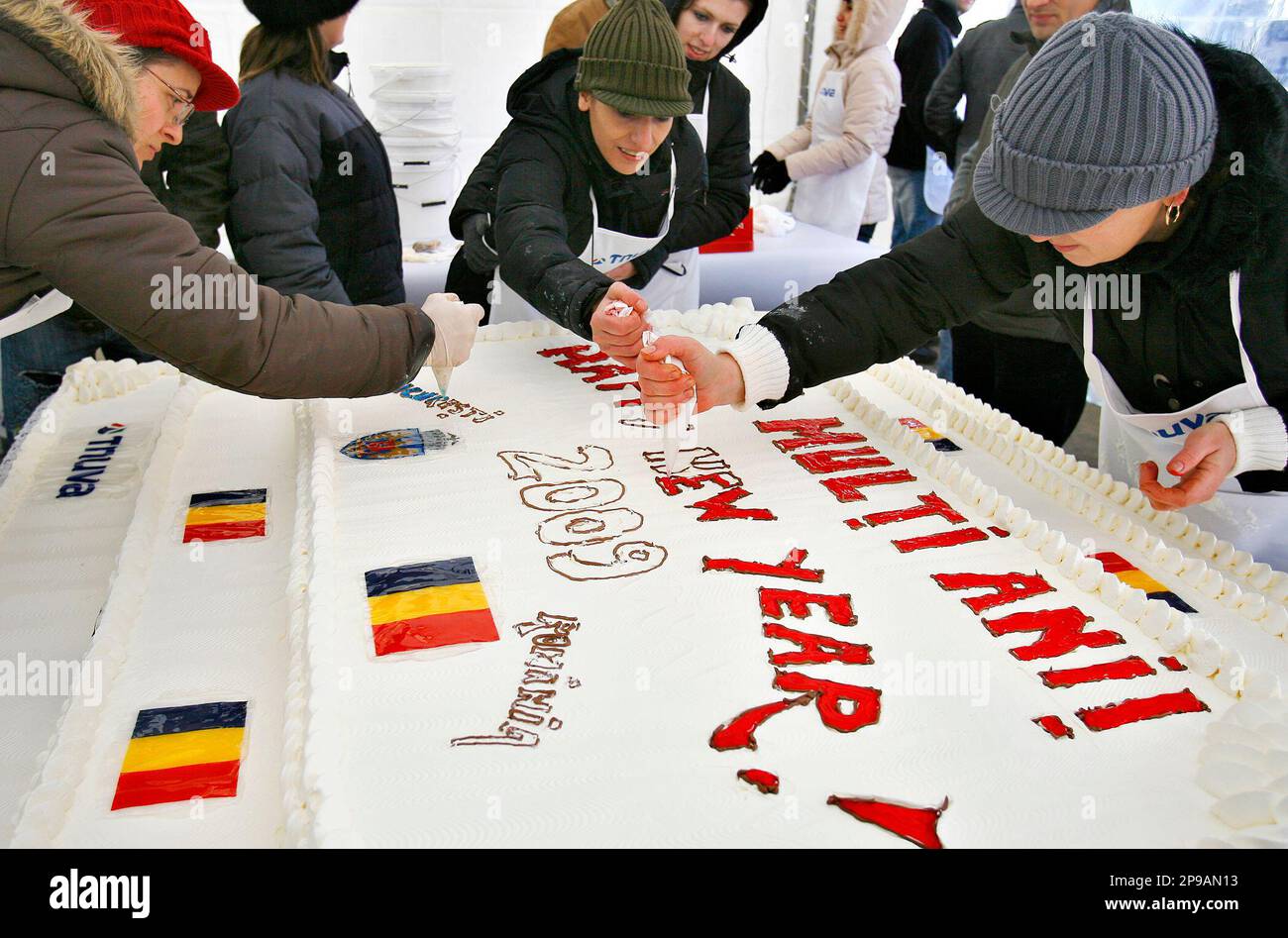 Women complete decorations on a fruit and cream cake in Bucharest ...