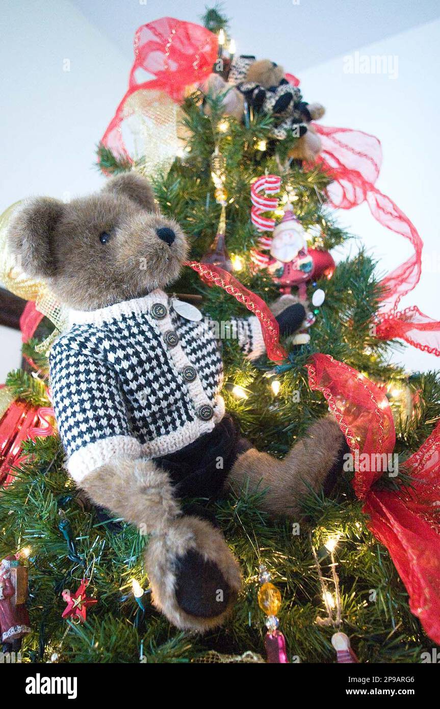 A teddy bear sits high on a Christmas tree in one of the rooms of the ...