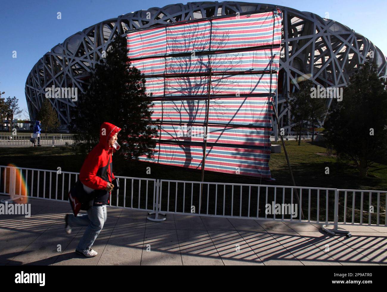 A Chinese man runs outside the "Bird's Nest" National Stadium that was ...
