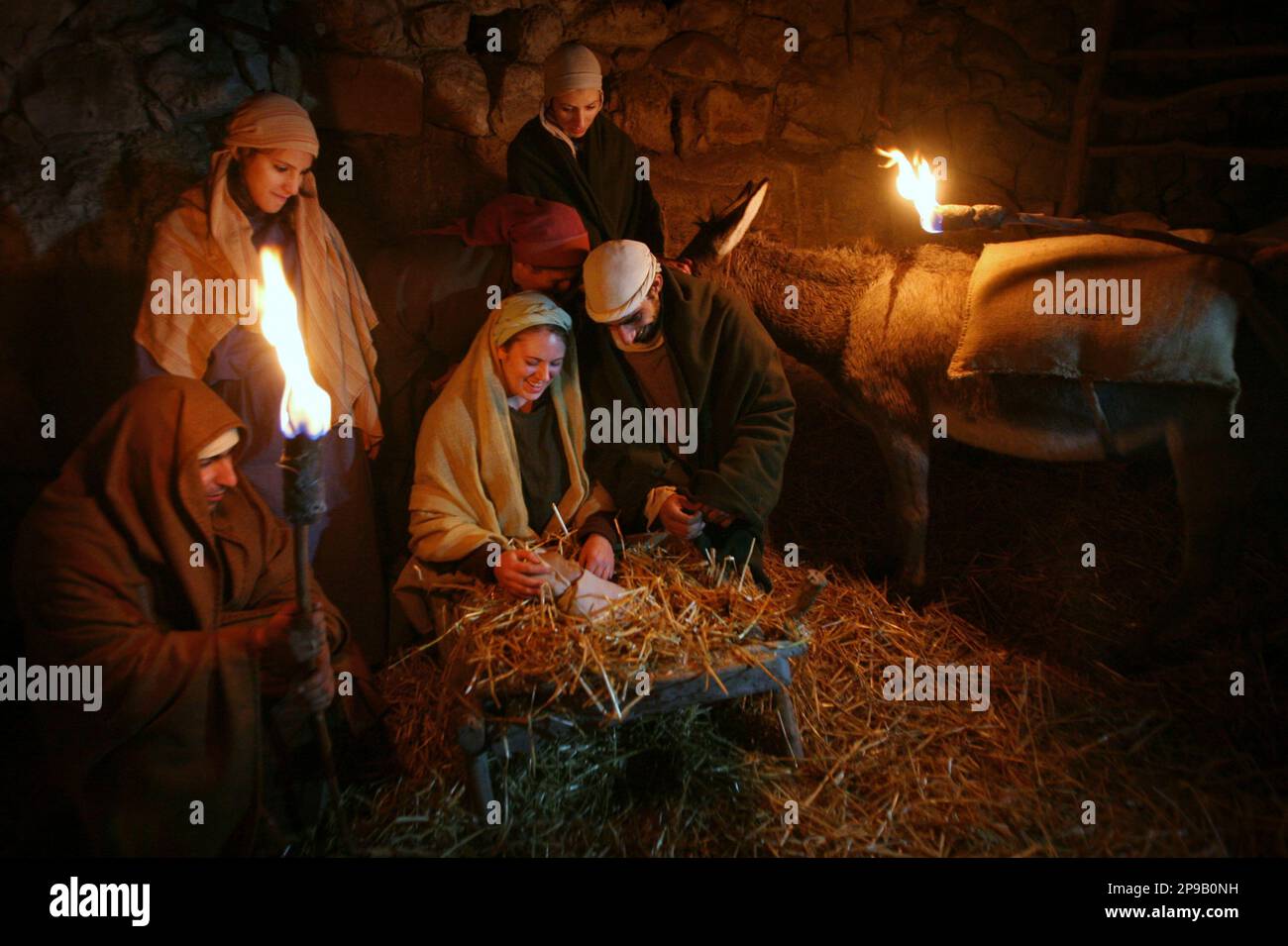 Palestinian Christian actors gather around a cradle with a doll as they ...