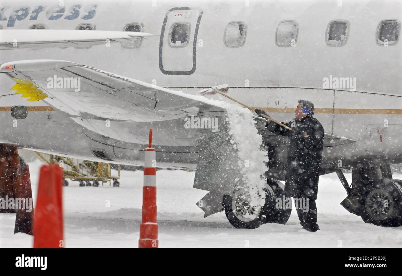 A pilot brushes snow off a wing during a safety check of a plane at ...