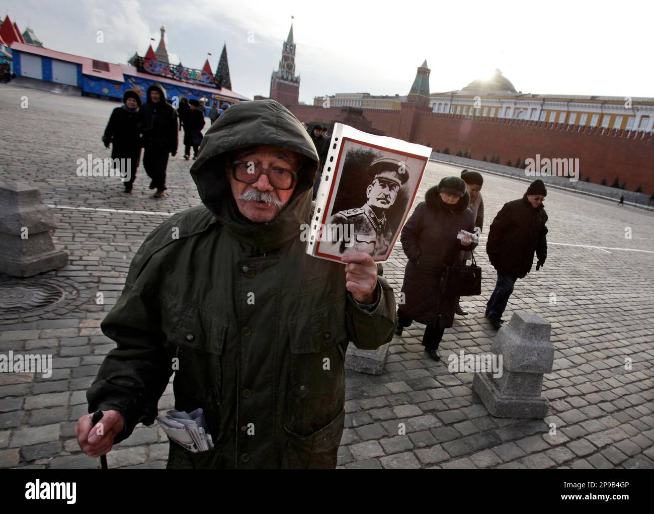 An elderly man holds up a portrait of Soviet dictator Josef Stalin to ...