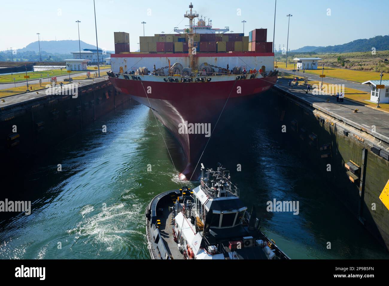 A cargo ship is guided by a tugboat through the Panama Canal's Cocoli ...