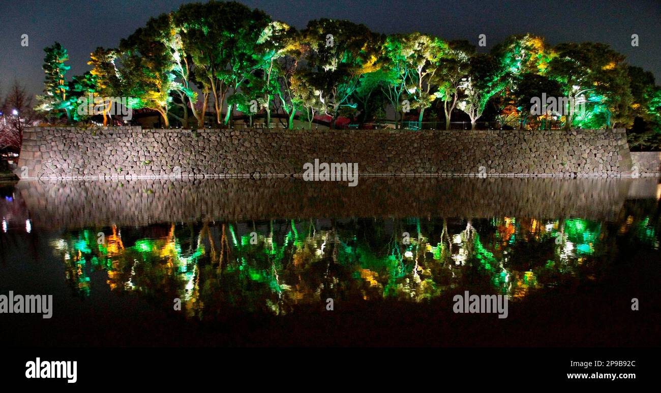Trees and stone walls of the imperial moat are illuminated during the ...