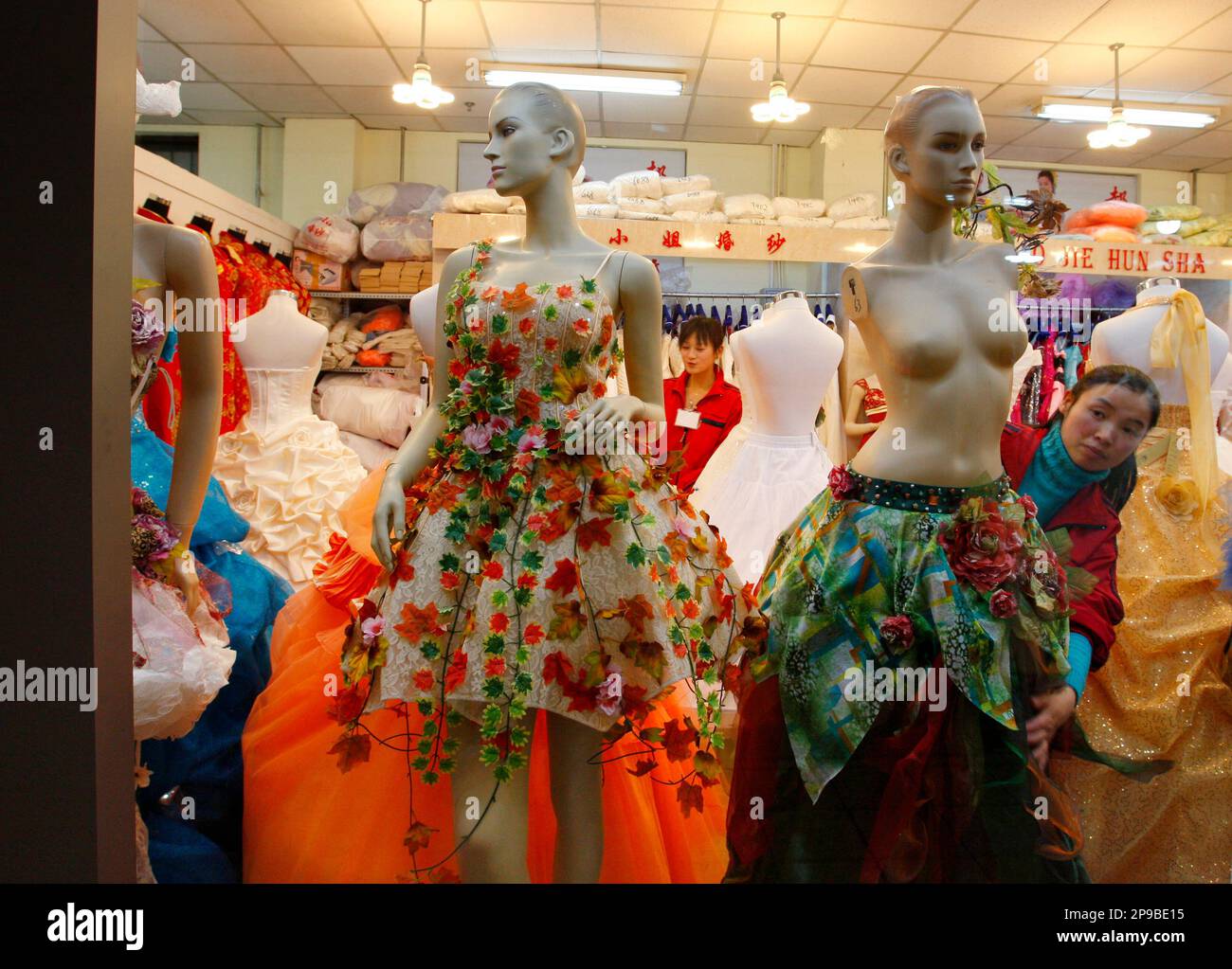 A Chinese sales clerk arranges a window display at a clothes shop in ...