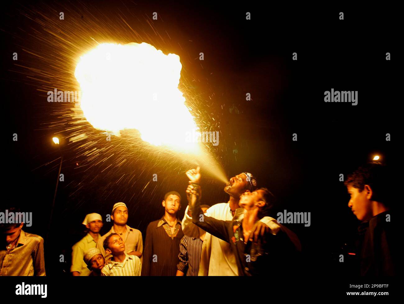 Devotees blow fire during a procession as part of a Muslim festival in ...