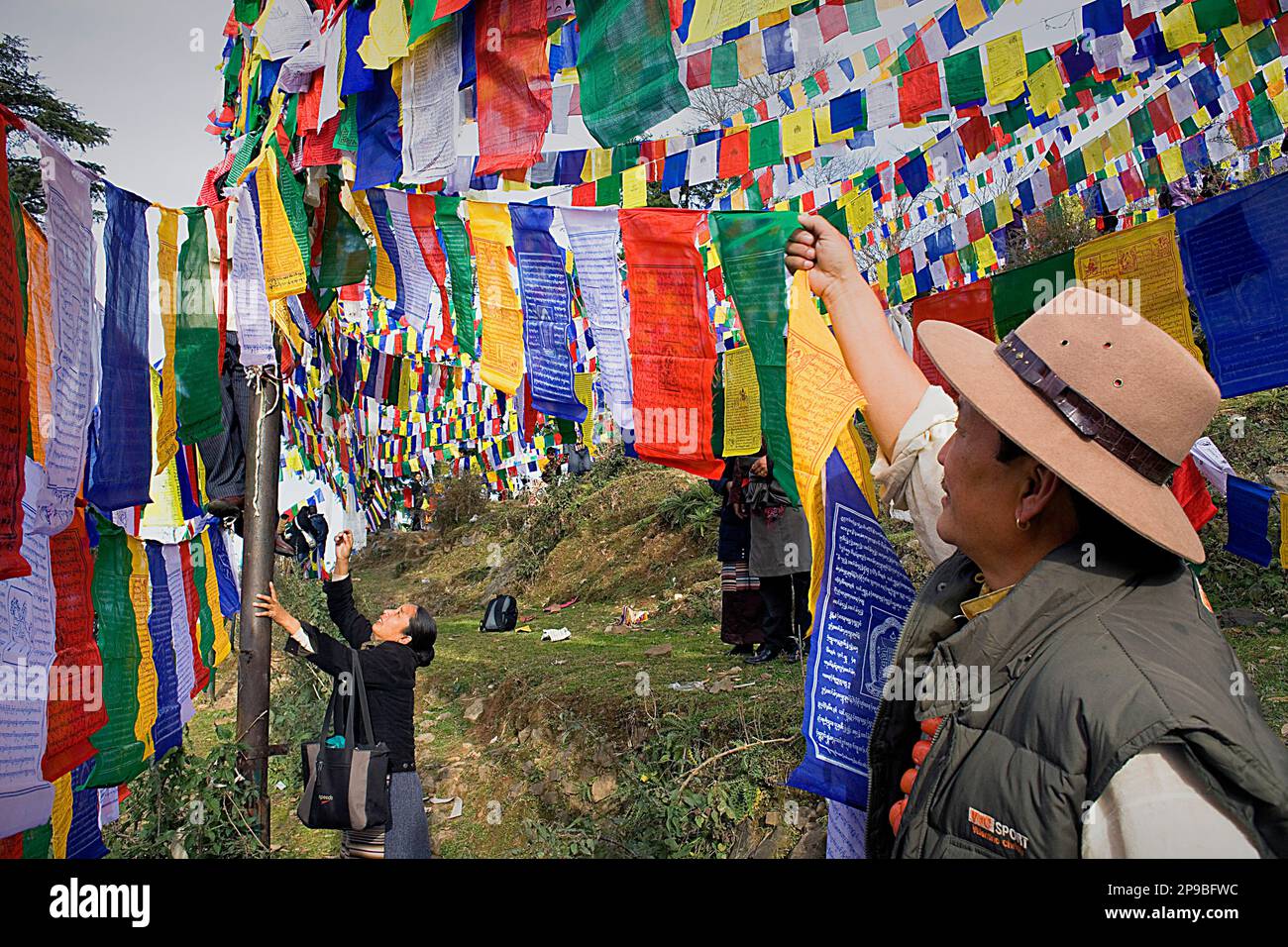 People hanging Tibetan prayer flags in Lhagyal Ri, near Tsuglagkhang ...