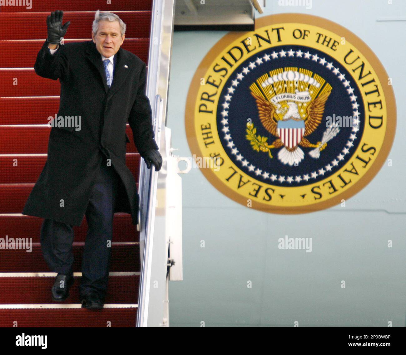 President George W. Bush waves as he walks down the stairs of Air Force ...