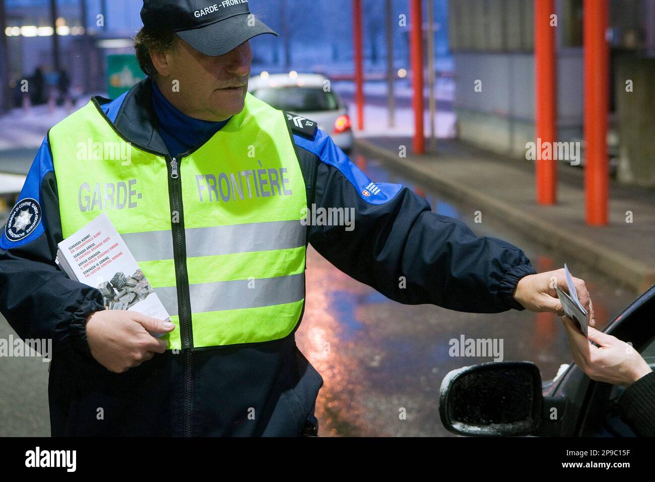 A Swiss border guard hands out a leaflet reading "Schengen is coming ...