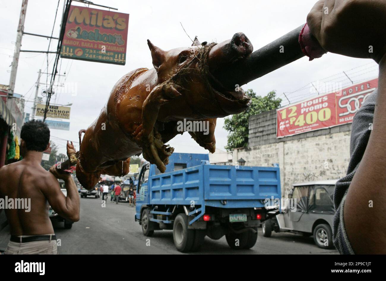 Workers carry a newly roasted pig, locally known as "lechon," to be ...