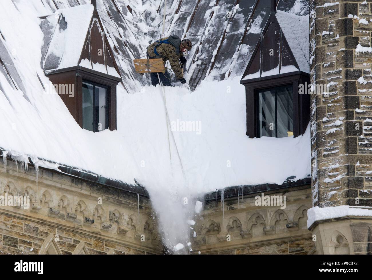 A worker clears snow off the roof of the Parliament Buildings in Ottawa ...