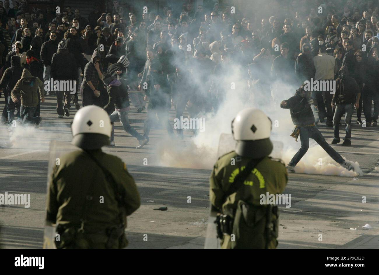 A protester kicks a tear gas canister in front of riot police, as ...