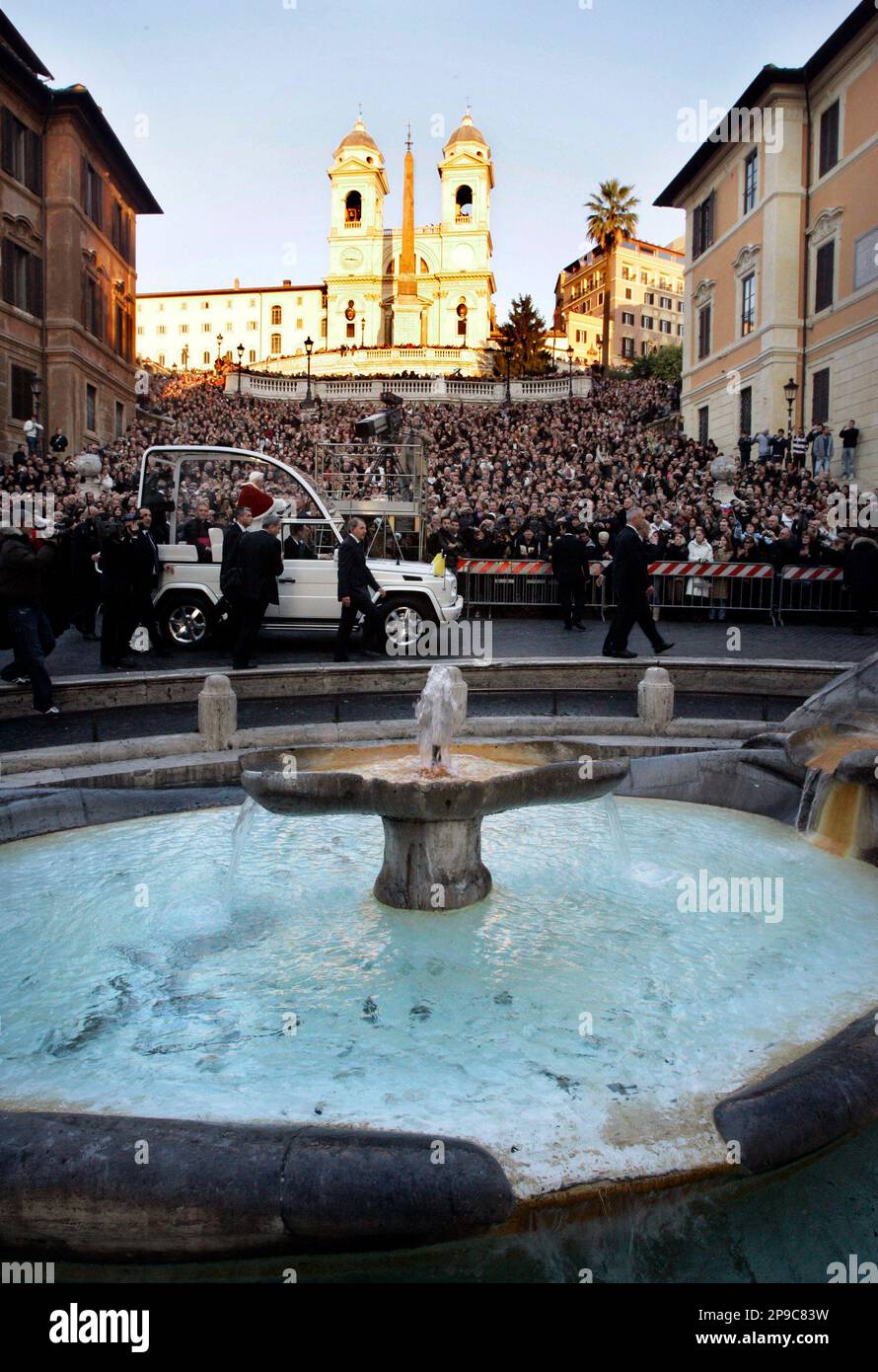 Pope Benedict XVI, standing on his popemobile, is driven past the ...