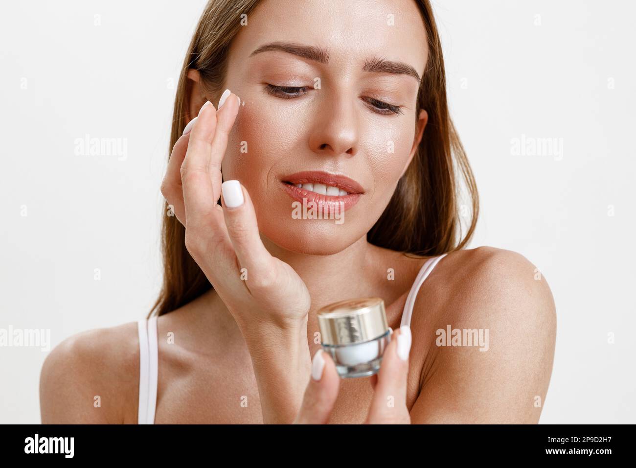 Close up face portrait of young woman applying cream to her face on ...