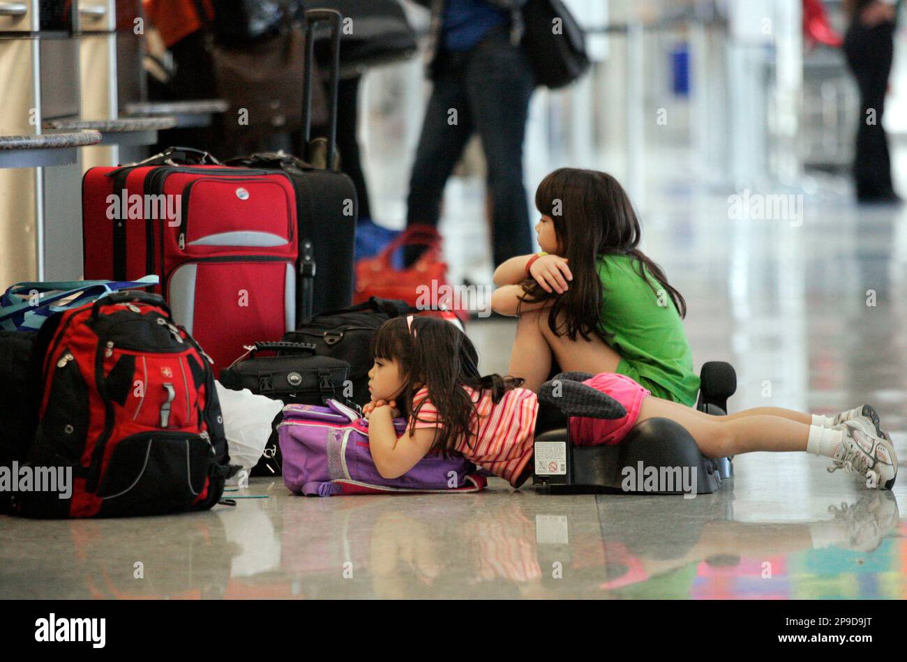 Kellyn Mendez, 4, front and her sisiter Ariana Mendez, 8, sit with their luggage as they wait in ...