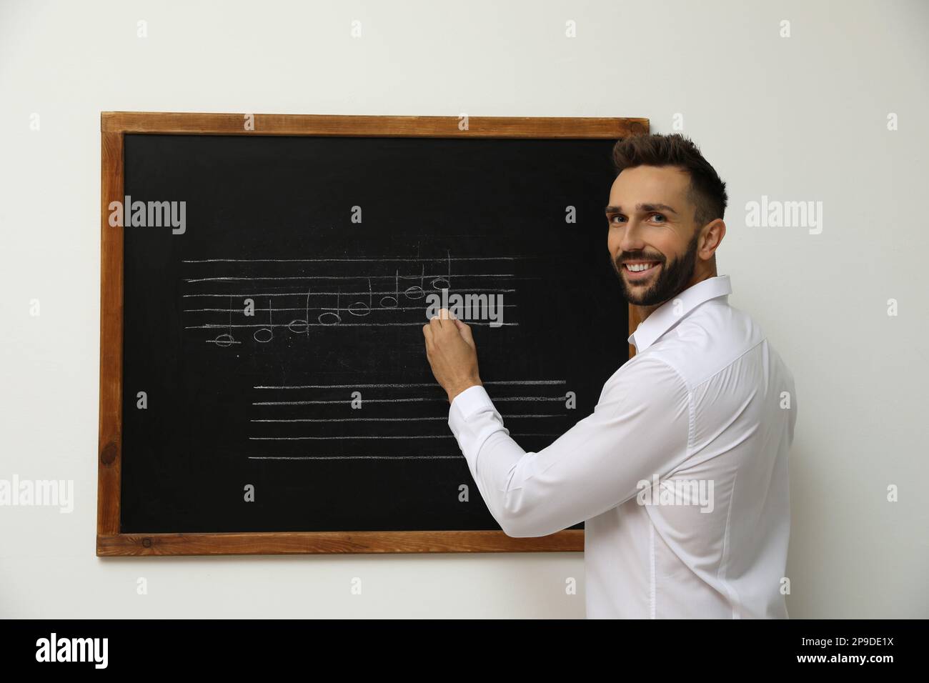 Teacher writing music notes with chalk on blackboard in classroom Stock ...