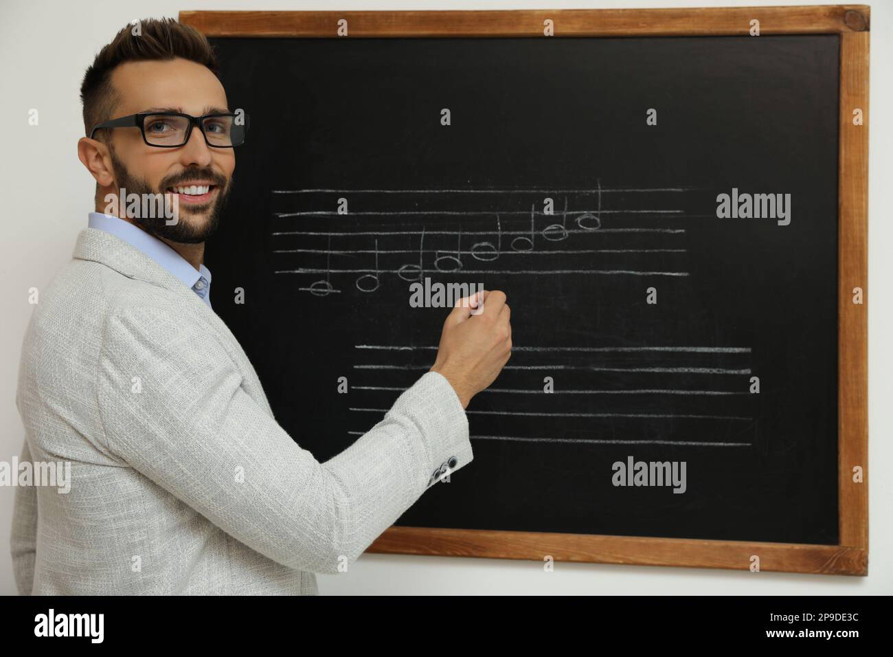 Teacher writing music notes with chalk on blackboard in classroom Stock ...