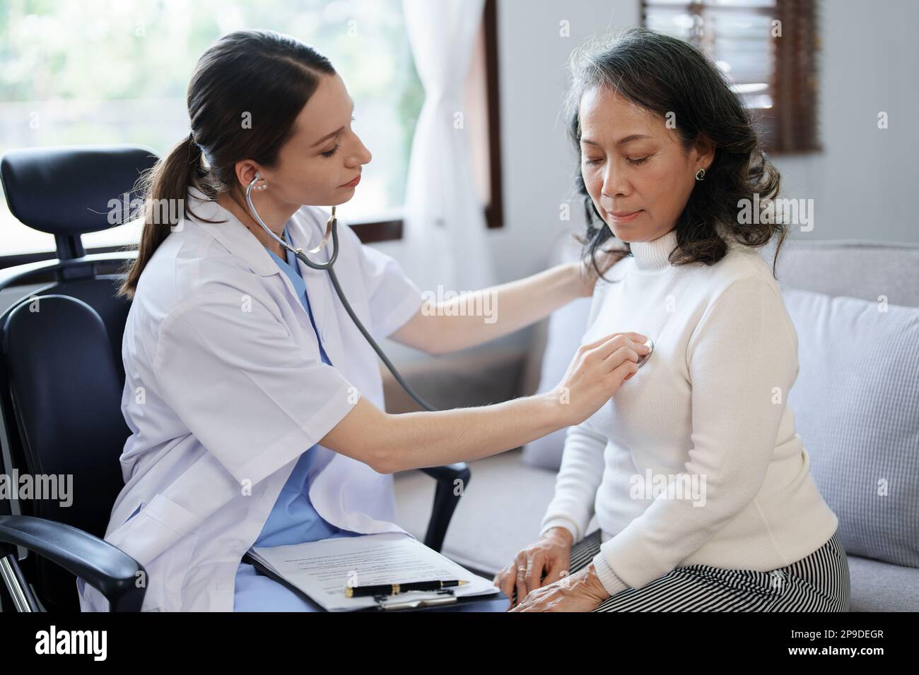 Portrait of a female doctor using a stethoscope to check the pulse of ...