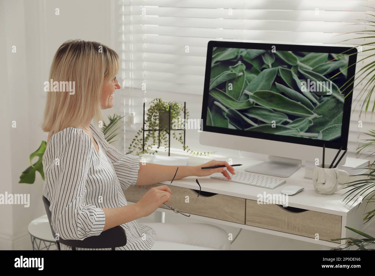 Woman working on computer at table in room. Interior design Stock Photo ...