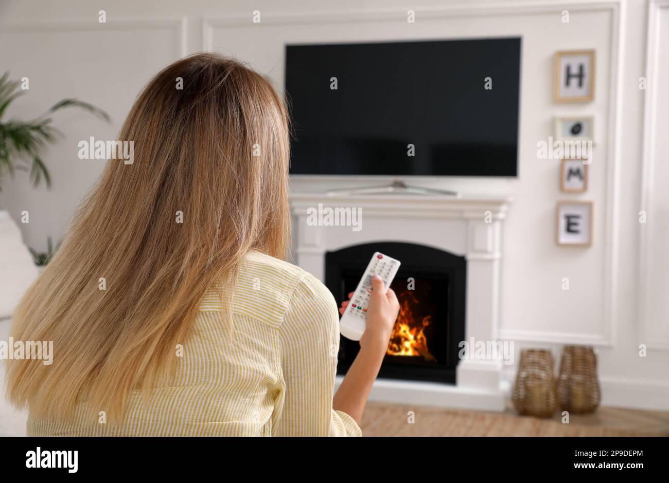 Young woman watching television at home, back view. Living room ...