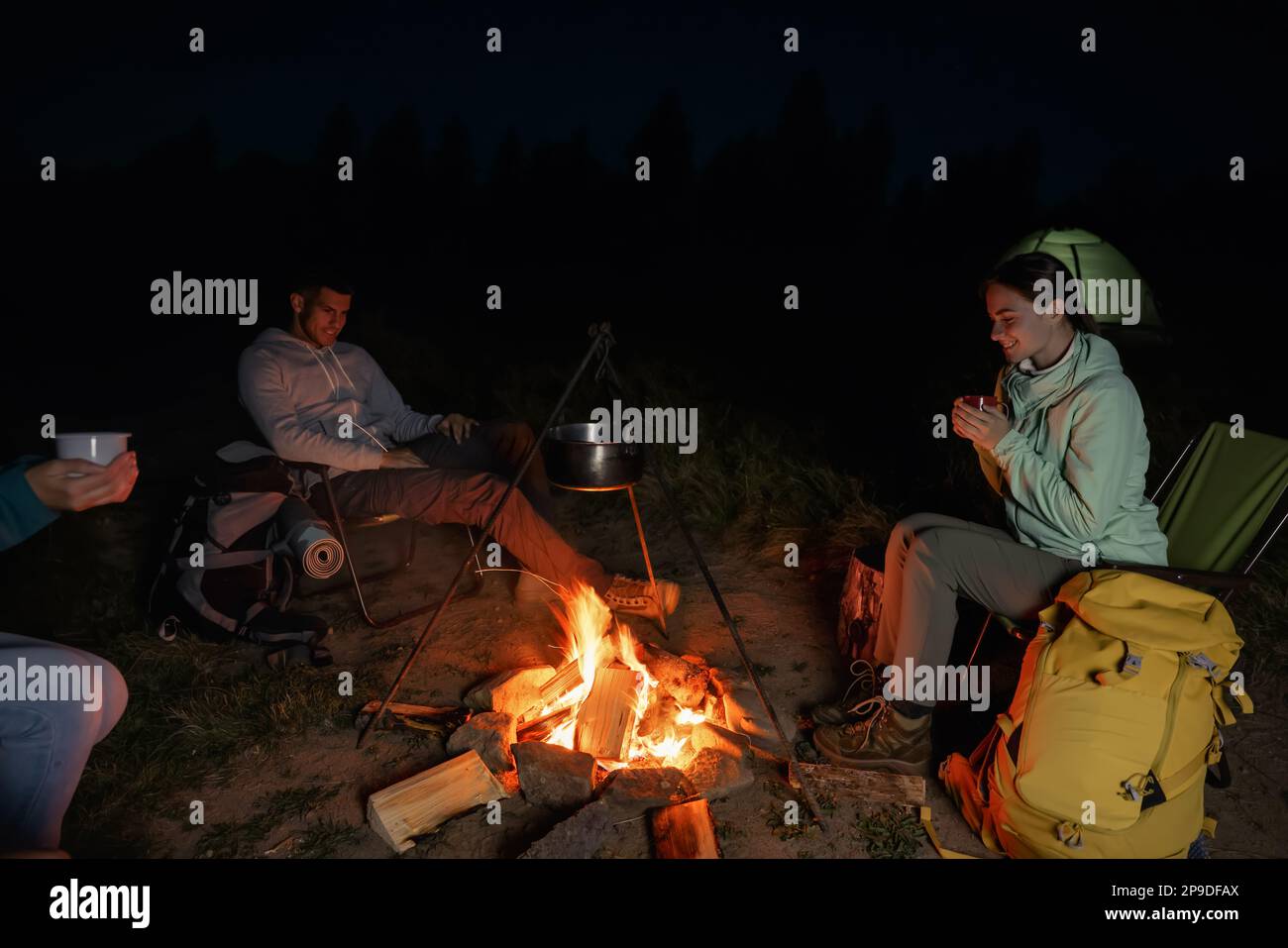 People sitting near bonfire in camp at night Stock Photo - Alamy