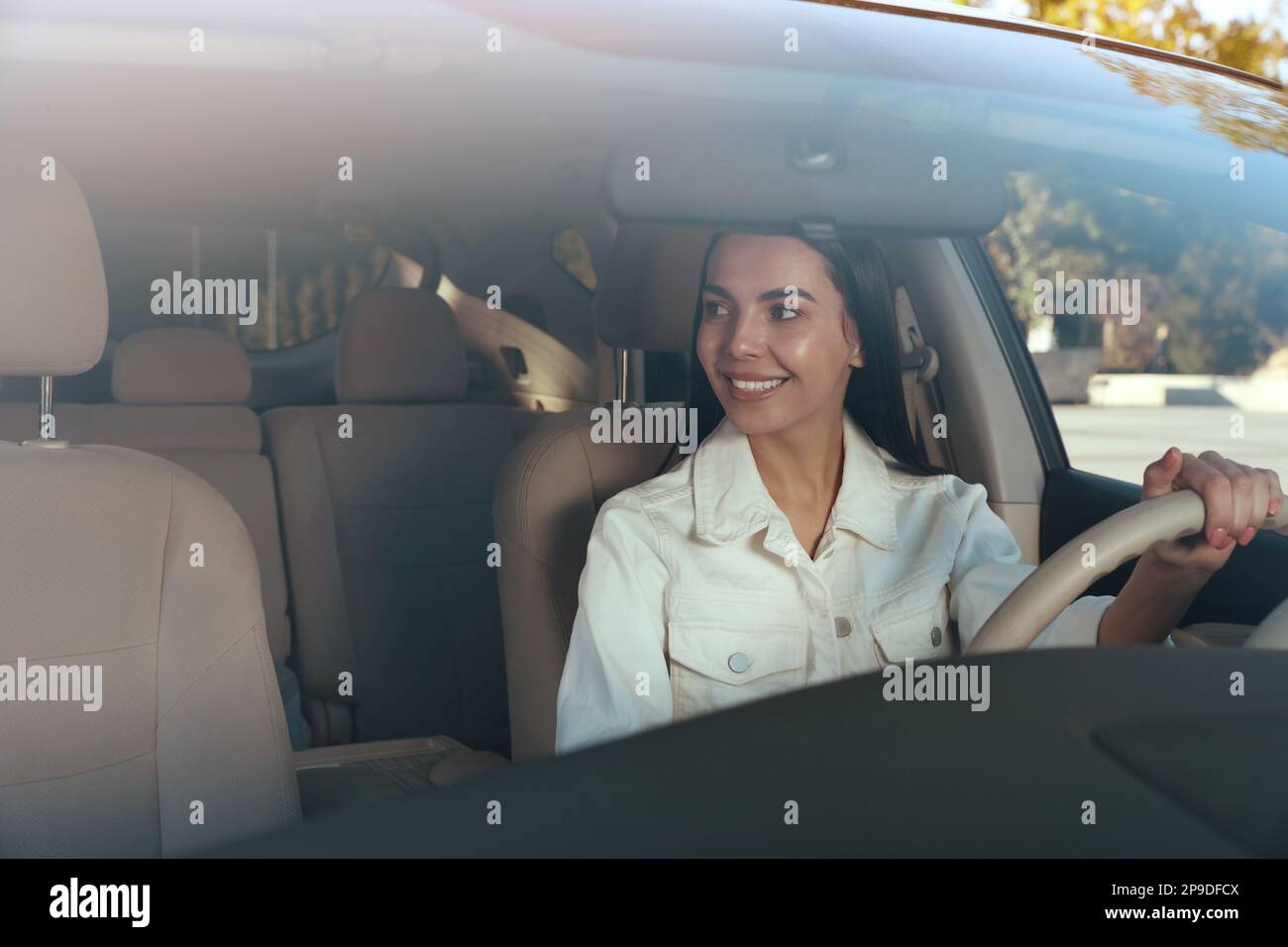 Beautiful young driver sitting in modern car, view through windshield ...