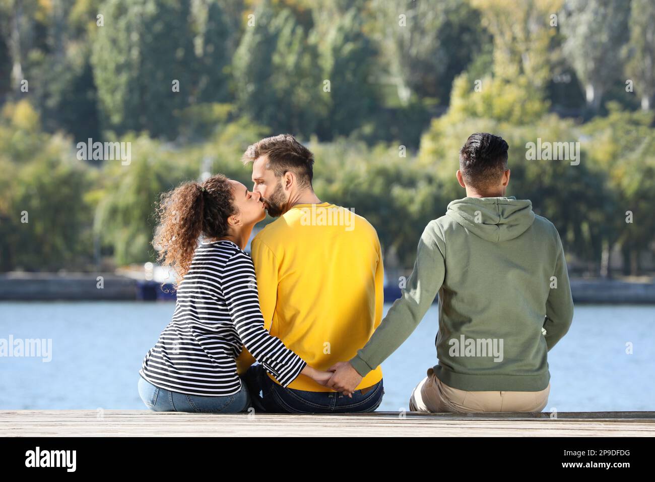 Woman holding hands with another man behind her boyfriend's back on ...