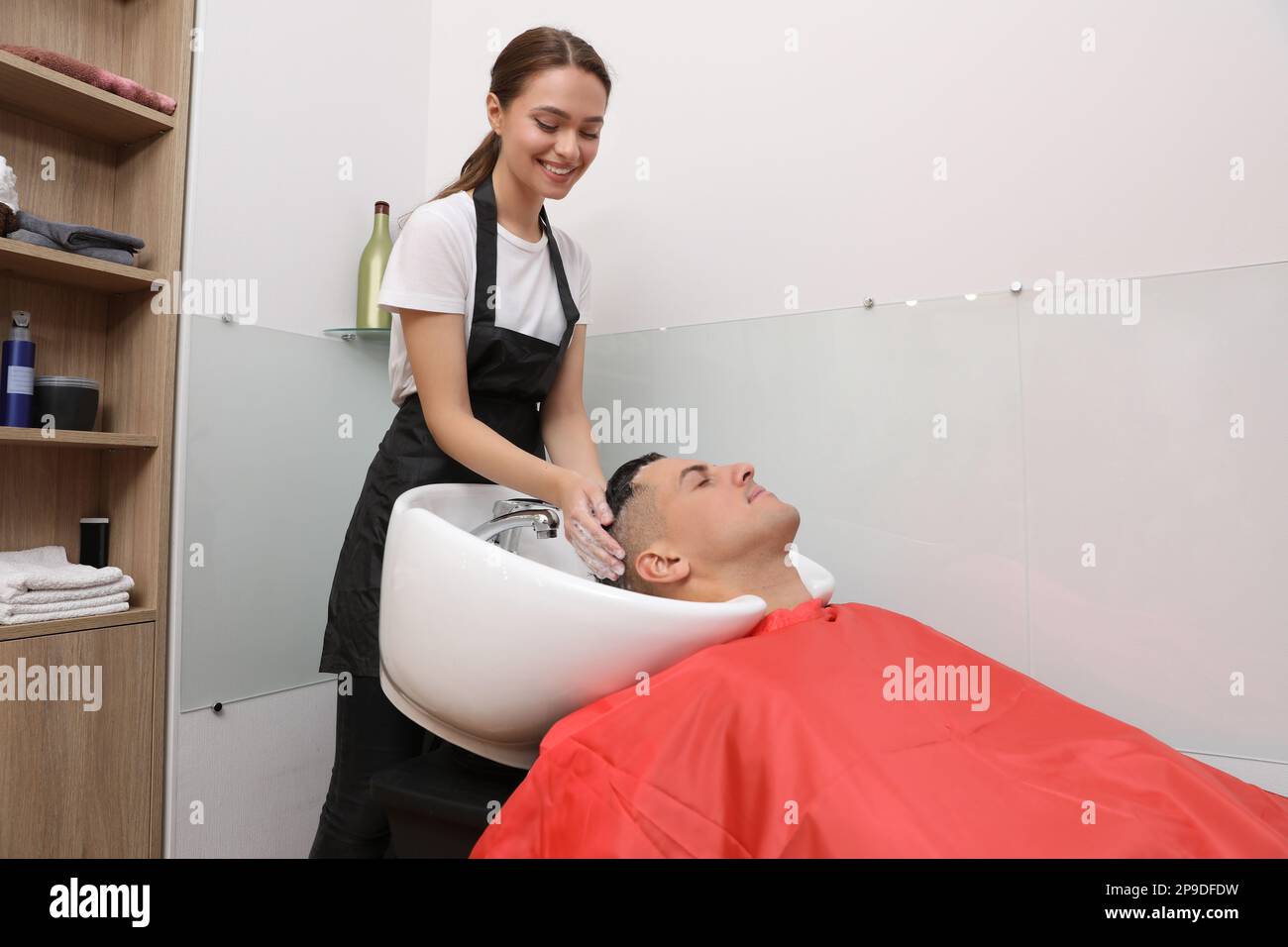 Professional hairdresser washing client's hair at sink in salon Stock ...