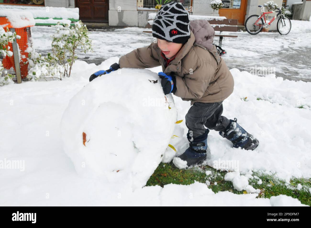 A boy builds a snowman in Aigle, Canton of Vaud, western Switzerland ...