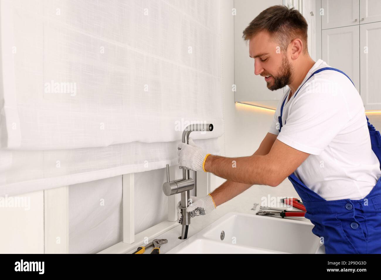 Professional plumber repairing water tap in kitchen Stock Photo - Alamy