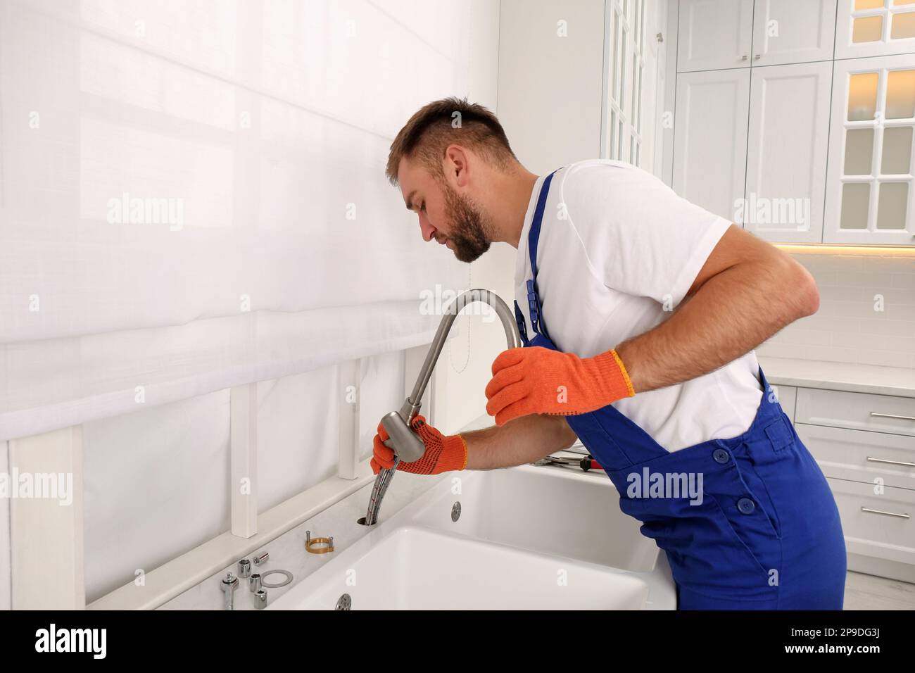 Professional plumber repairing water tap in kitchen Stock Photo - Alamy