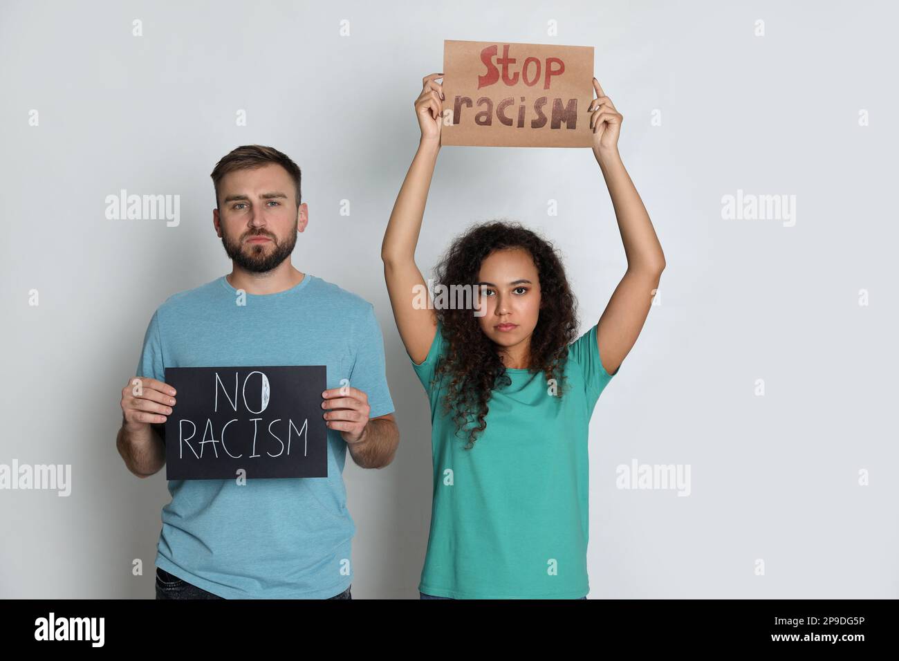 Young man and African American woman holding signs on grey background ...