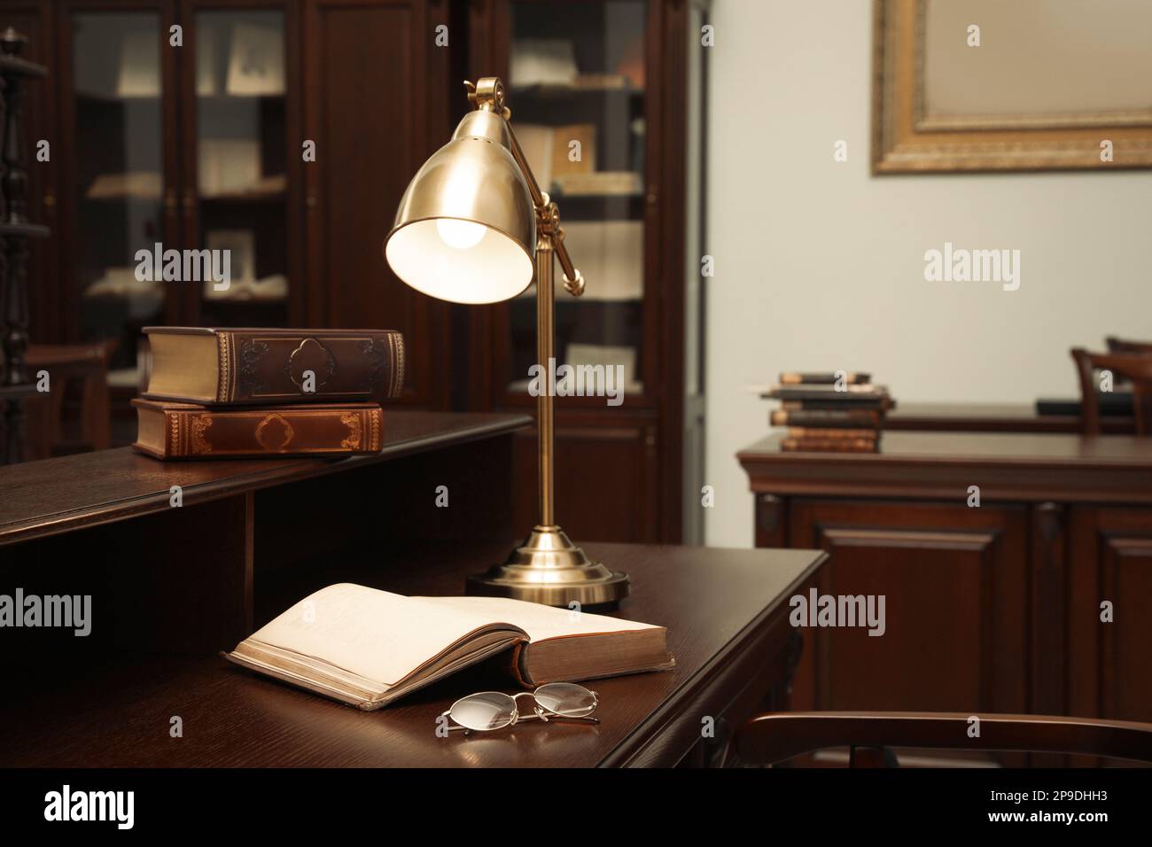Books, glasses and lamp on wooden table in library reading room Stock ...