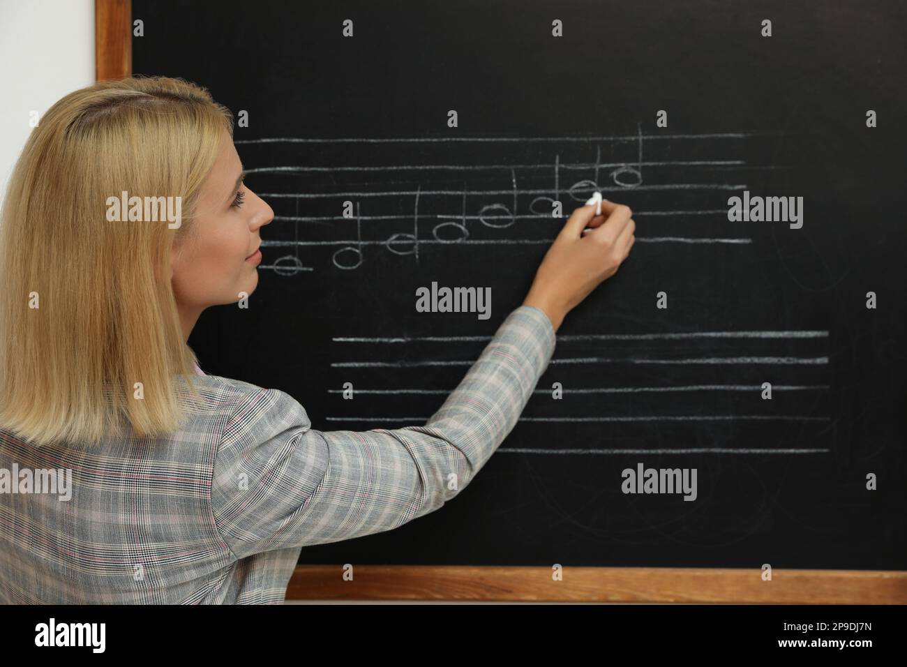 Teacher writing music notes with chalk on blackboard in classroom Stock ...