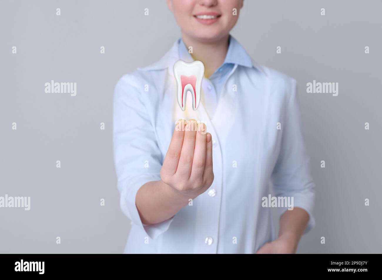 Dentist showing virtual model of tooth on light grey background ...
